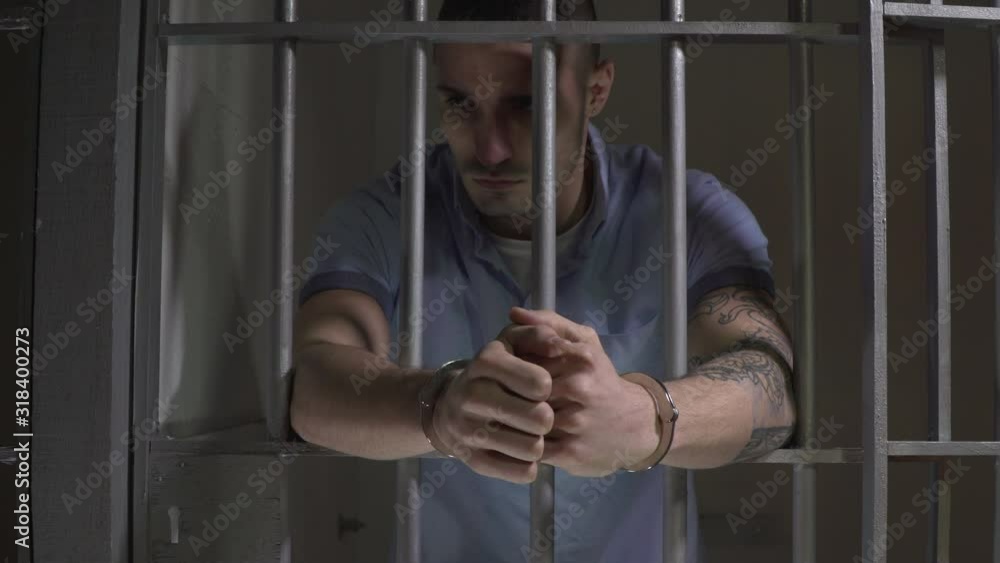 Male Prisoner behind bars in A Jail / Prison Cell. He is in Handcuffs ...