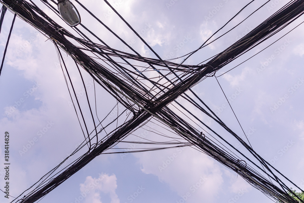Multiple electric wires crossing in the air against blue sky, view at a ...