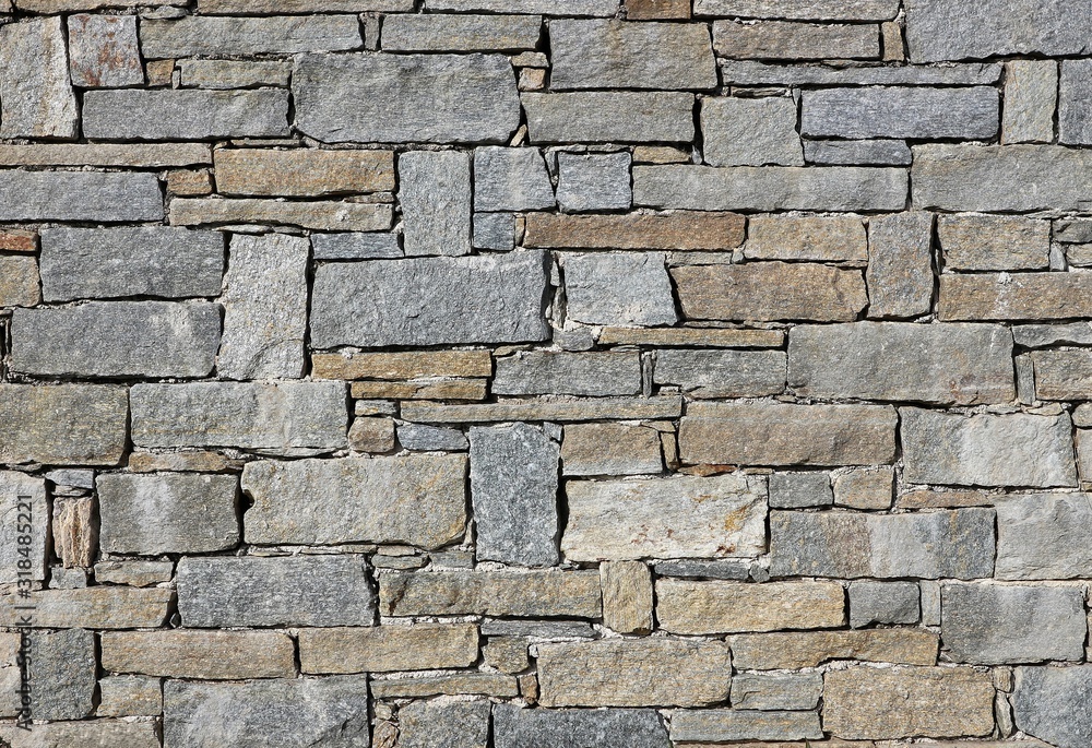 Stone wall made from irregular shaped natural rocks. The colors are ...