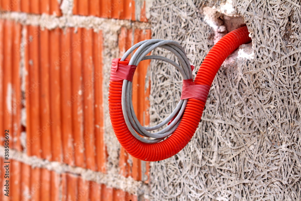Twisted electrical wire wrapped in grey rubber insulation within red ...