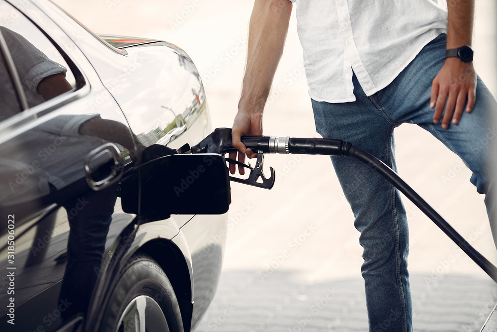 Man on a gas station. Guy refuelong a car. Male in a white shirt. Stock ...