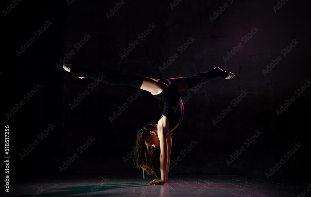 Teenage gymnast in black leotard, knee socks and ballet shoes ...