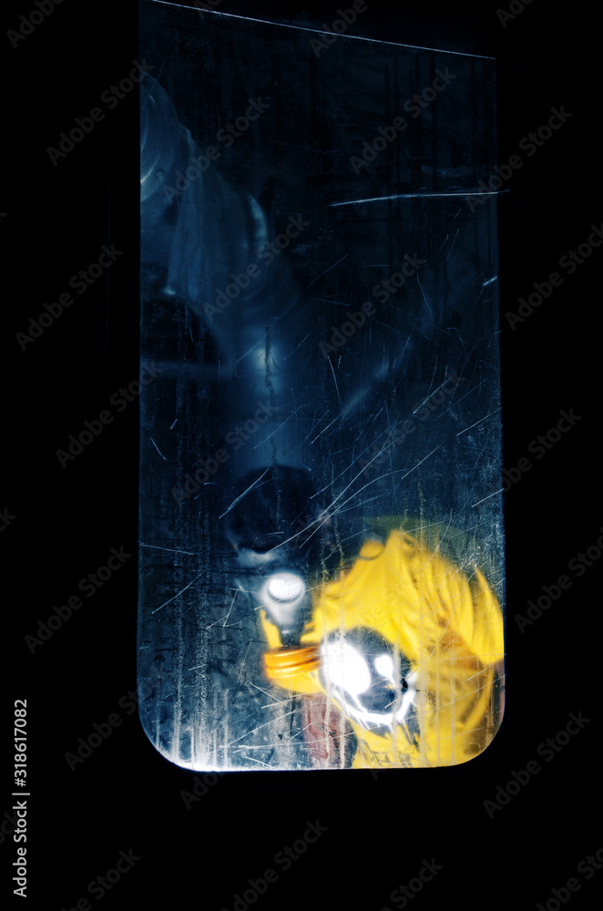 A scary man with reflection eyes in an industrial setting wearing a ...
