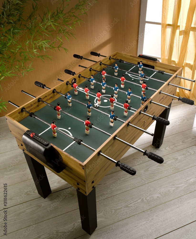 Table foosball, football. located in a room with a wooden floor and ...