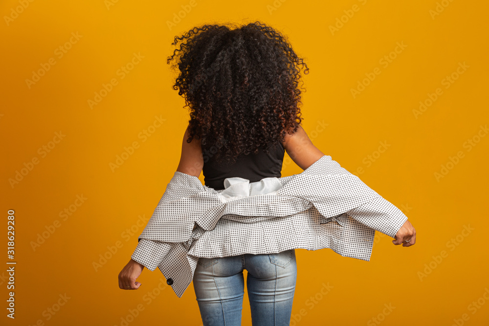 Young black woman on her back with afro hairstyle on yellow background ...