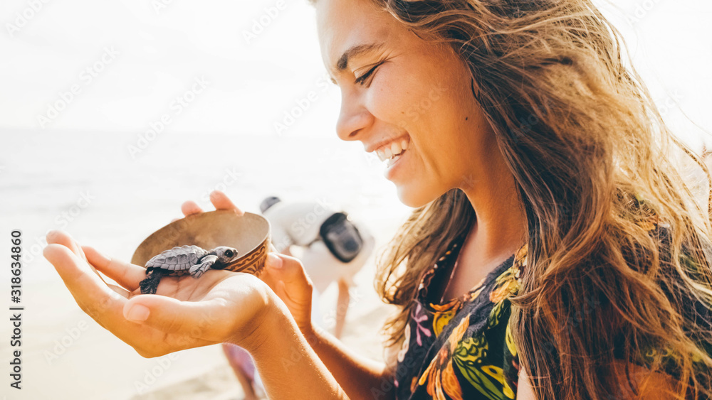 Women with flapping hair hold wooden bowl with newborn turtle,close up ...