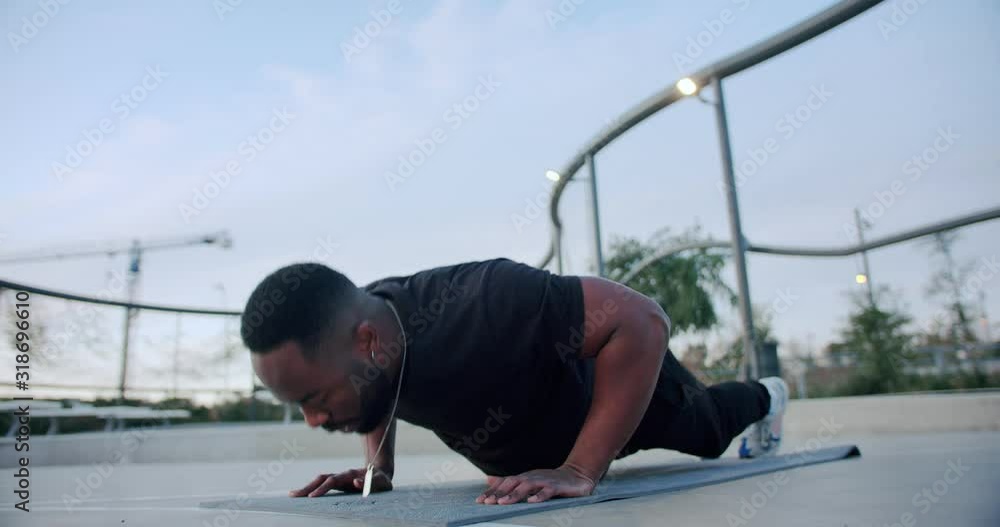 Strong healthy African man doing fitness exercises push ups on mat ...