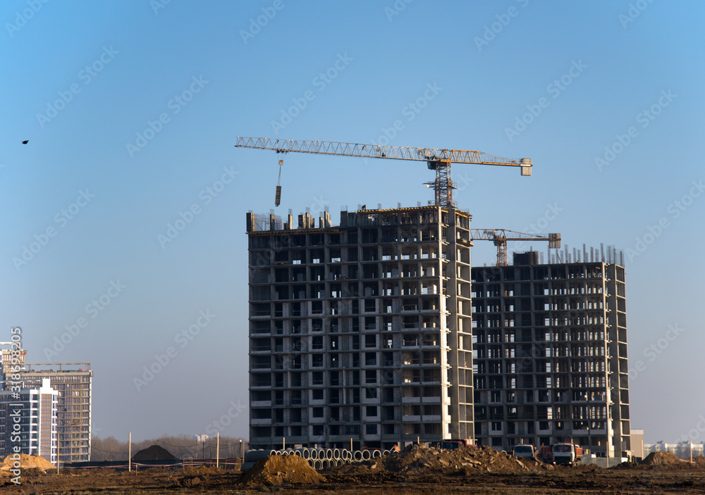 Tower crane lifts the block for building under construction at background blue sky at sunny day ...