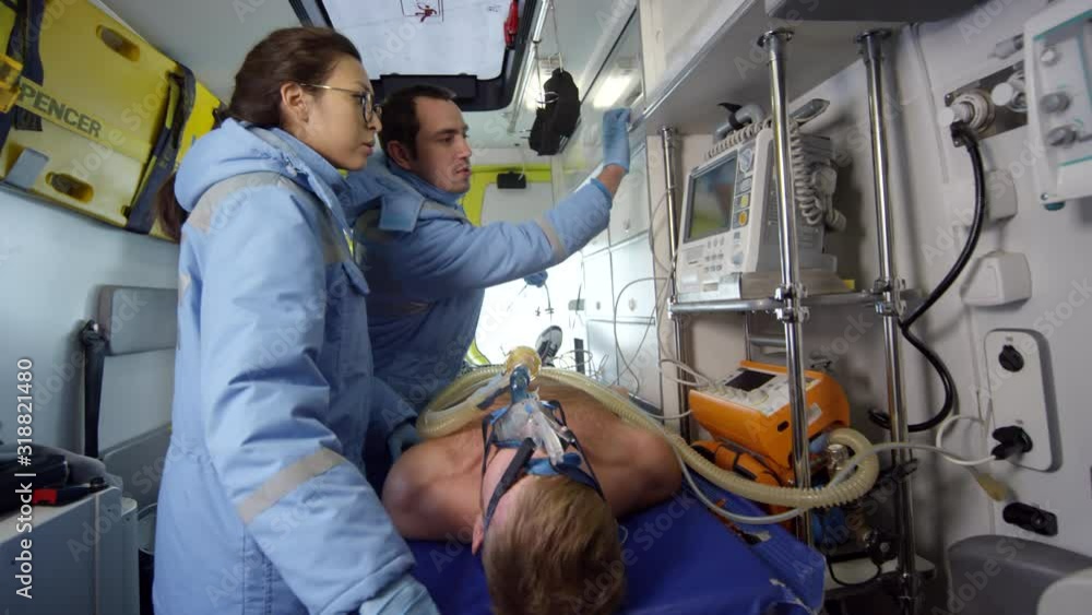 Handheld shot of male and female paramedics in uniform riding in back ...
