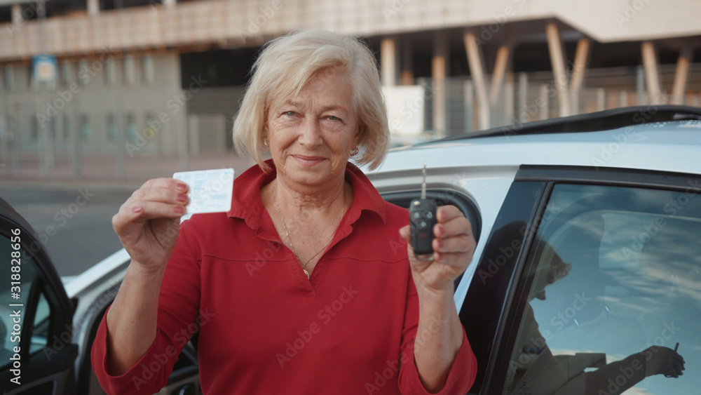 Beautiful senior woman standing with driver's license holding car keys ...