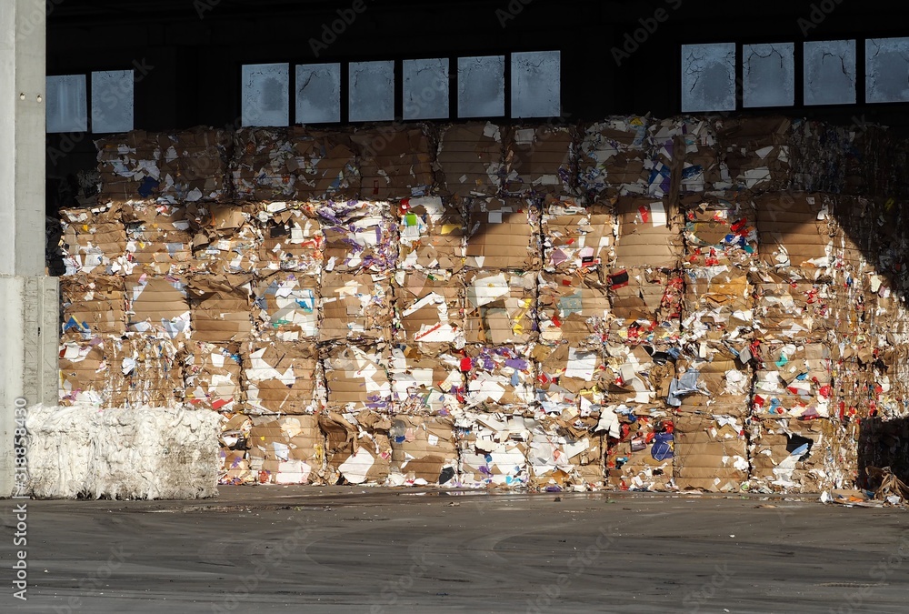Lined up stacks of cardboard and waste paper in a recycling plant ...