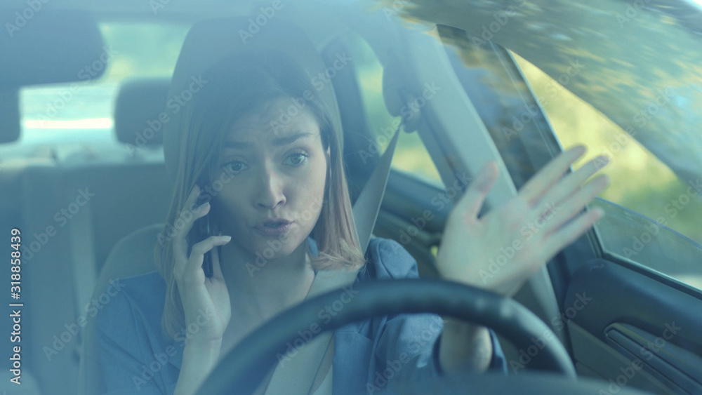 Angry young woman driver talking by phone while driving a car serious ...