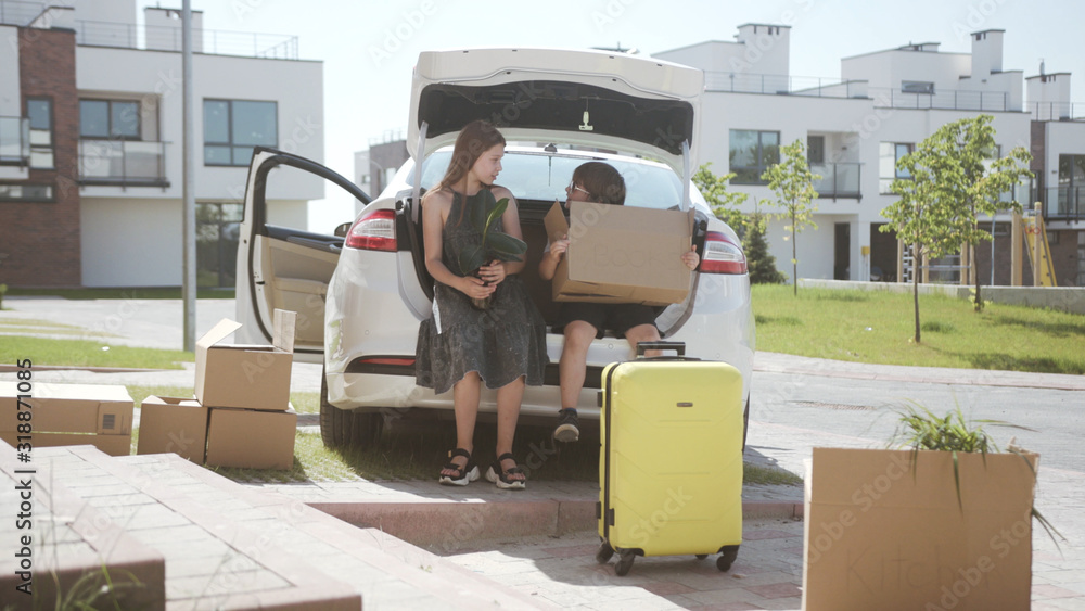 Two happy children siblings talking together sitting in the car trunk ...