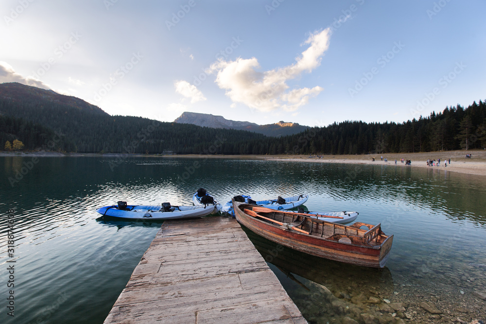 Mountain lake sunrise landscape.Old wooden boat and blue kayaks at the ...