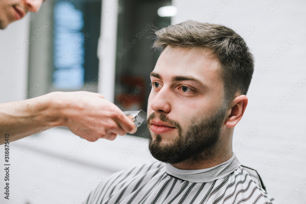 Foto de Adult male model with beard trimming at barber shop. Close up ...