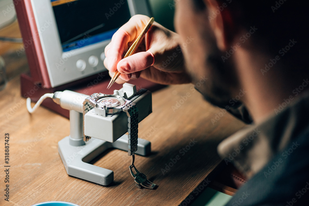 Selective focus of clockmaker working with wristwatch and watch tester ...