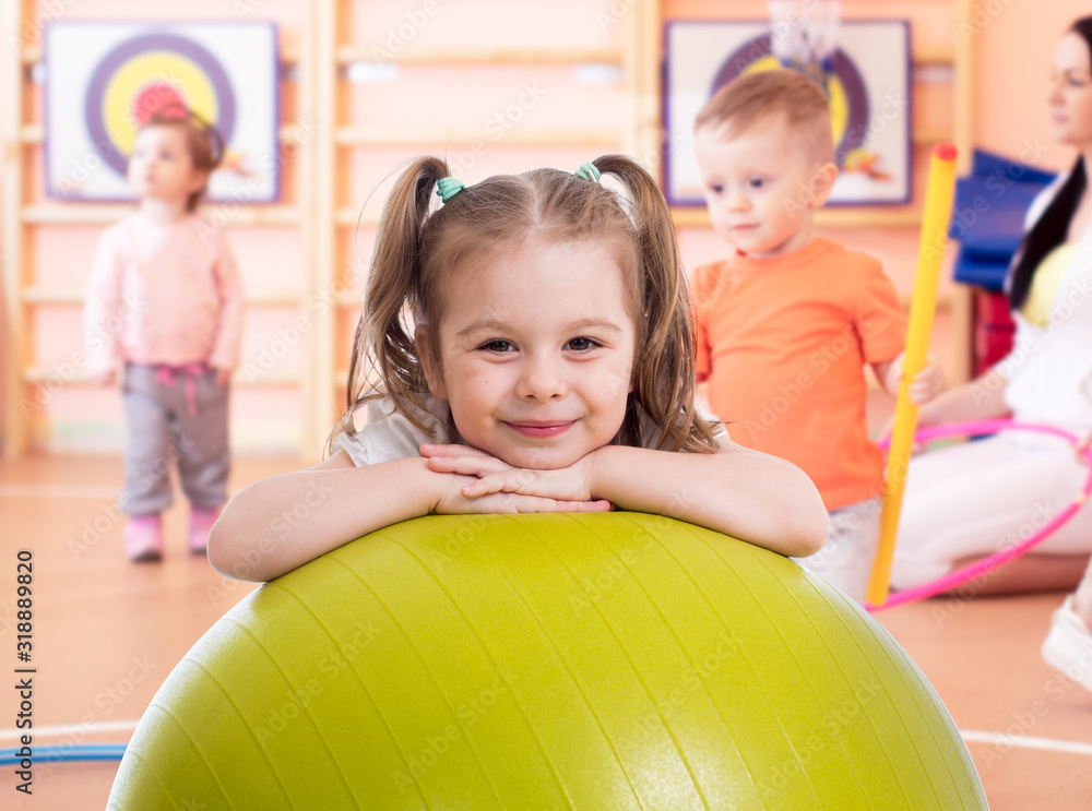 Smiling pretty child with fitness ball in gym. Gym class for preschool ...