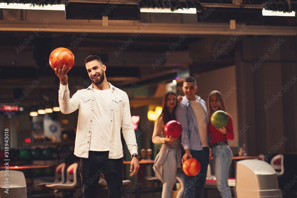 Beautiful group of young people posing in a bowling alley with a ball ...