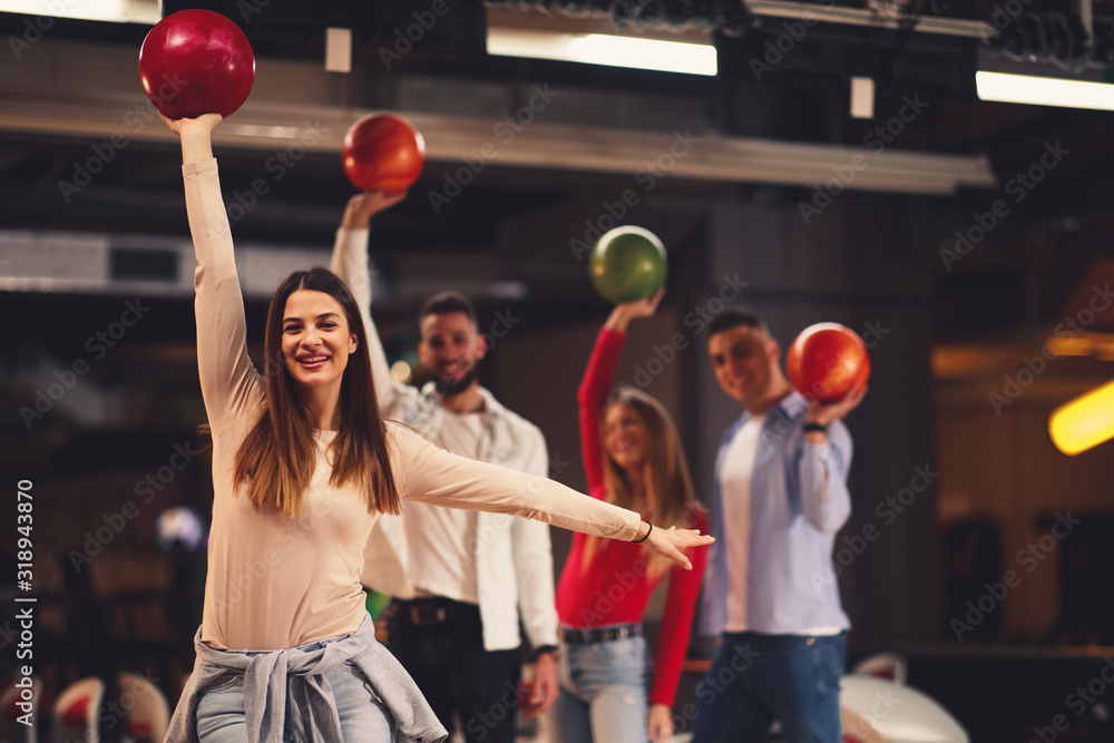 Beautiful group of young people posing in a bowling alley with a ball ...