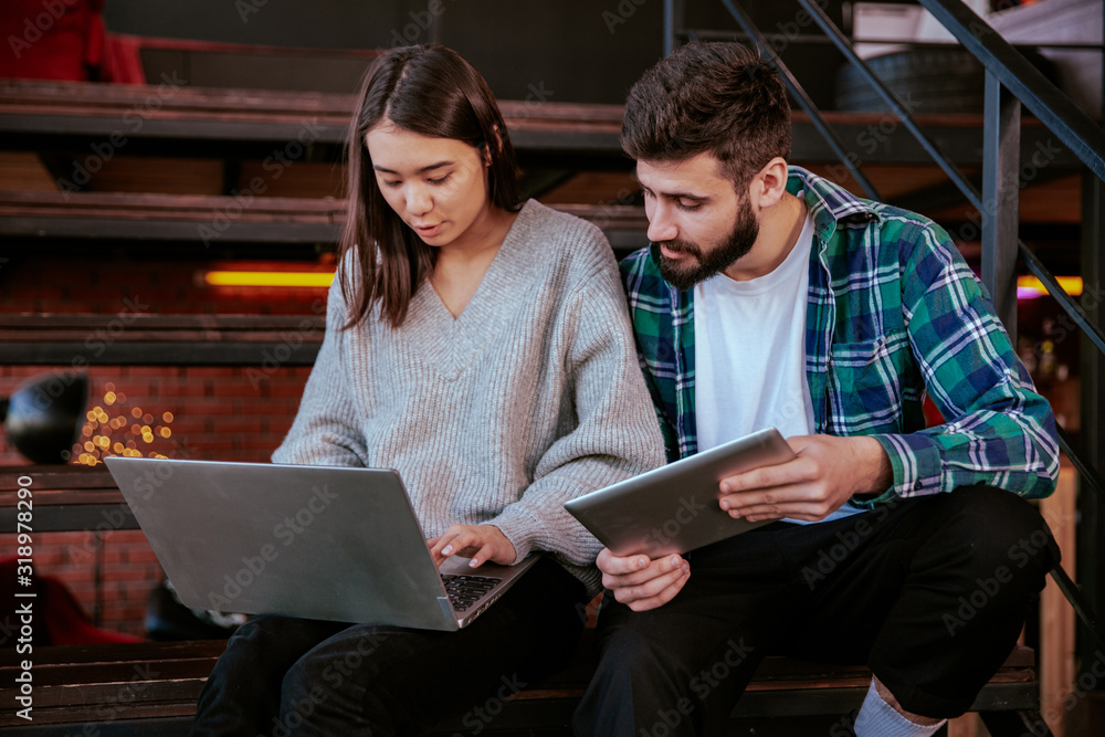 Two attractive young office workers analyzing the plan of work using ...