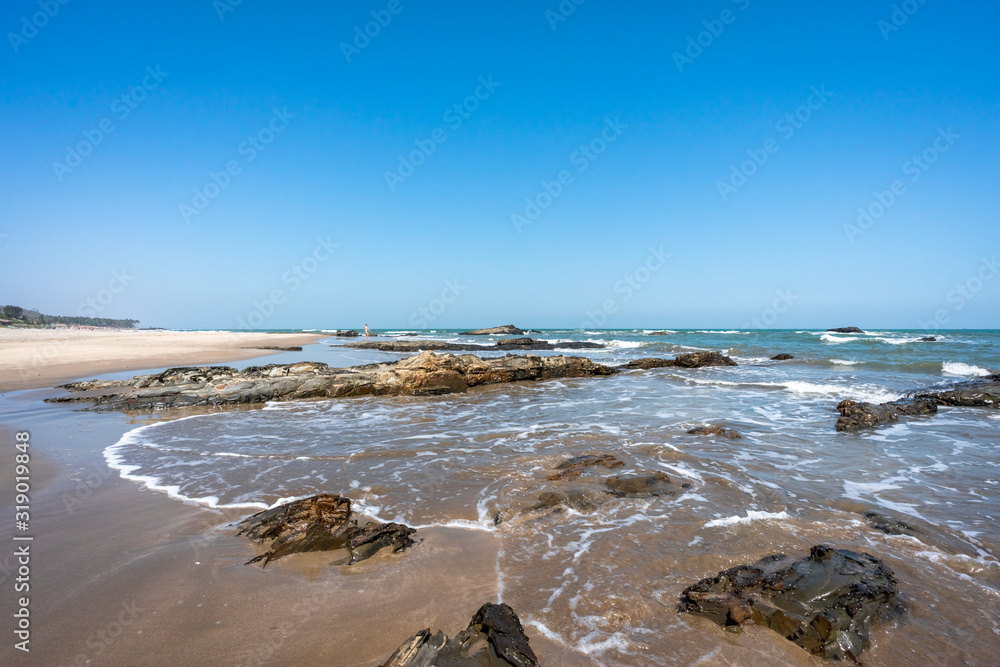 Large boulders on the shore. Waves of surf roll on the shore, breaking ...