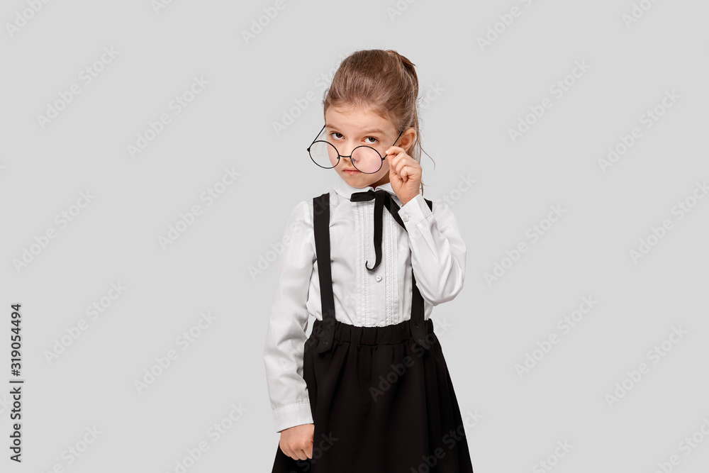 girl in a school uniform holds round glasses and looks inquiringly at ...