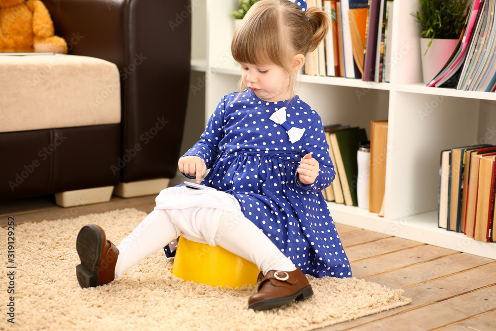 Cute little girl sit on her chamber pot do caca playing with cellphone ...