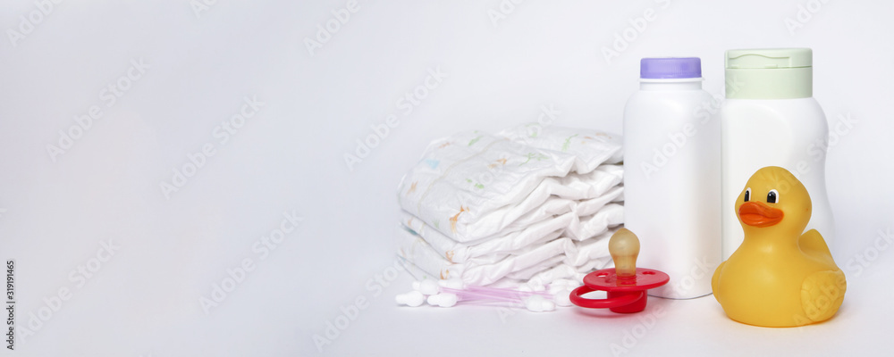 Set of baby accessories for hygiene on light table with toy, diapers ...