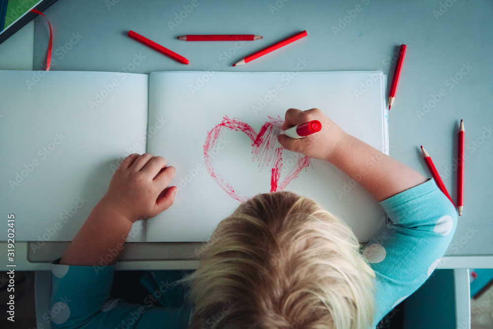 Little girl drawing red heart at white paper within red pens and ...