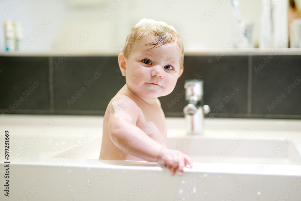 Cute adorable baby taking bath in washing sink and playing with water ...