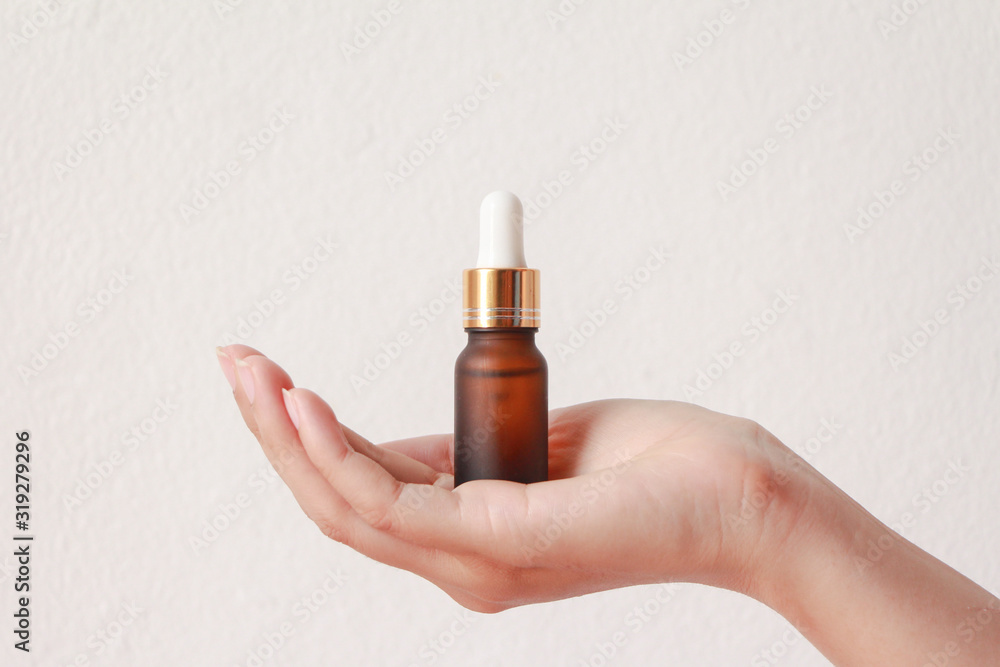 Woman hands holding facial essential oil or serum packaging on white ...