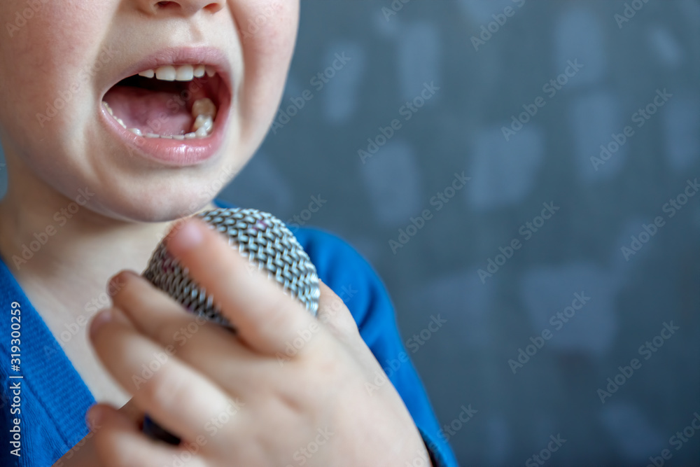 charming kid sings into microphone and opens her mouth wide with milk ...