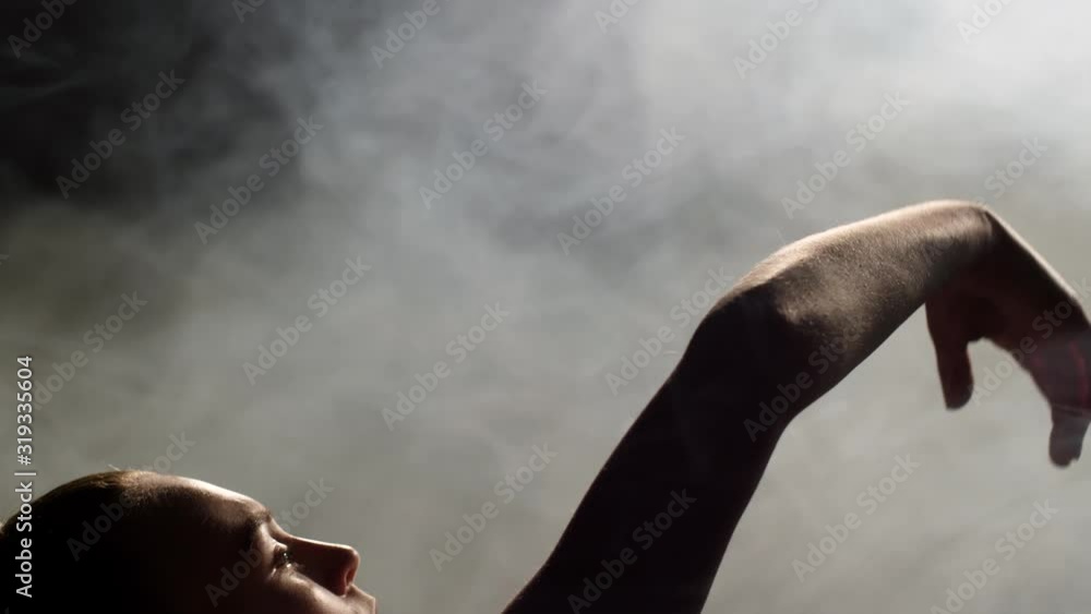Close-up profile of tender beautiful woman dancer raising her hand in ...