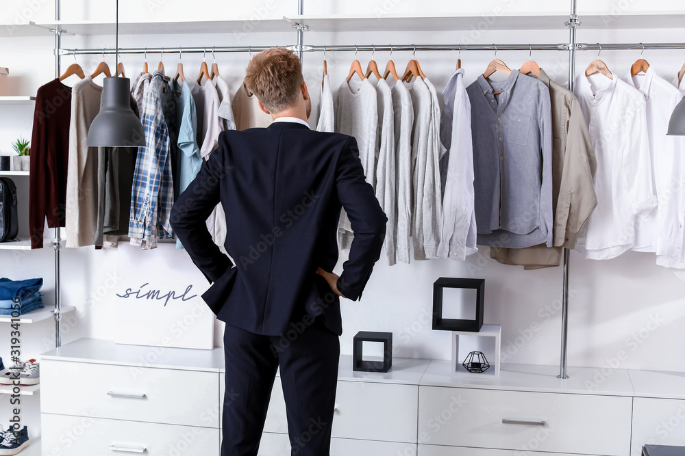 Handsome man choosing clothes in dressing room Stock Photo | Adobe Stock