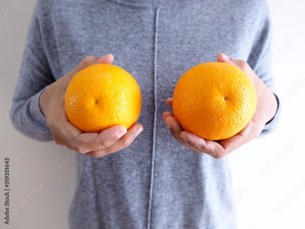 Bright yellow oranges in hands of Asian woman, Chest problems and size ...
