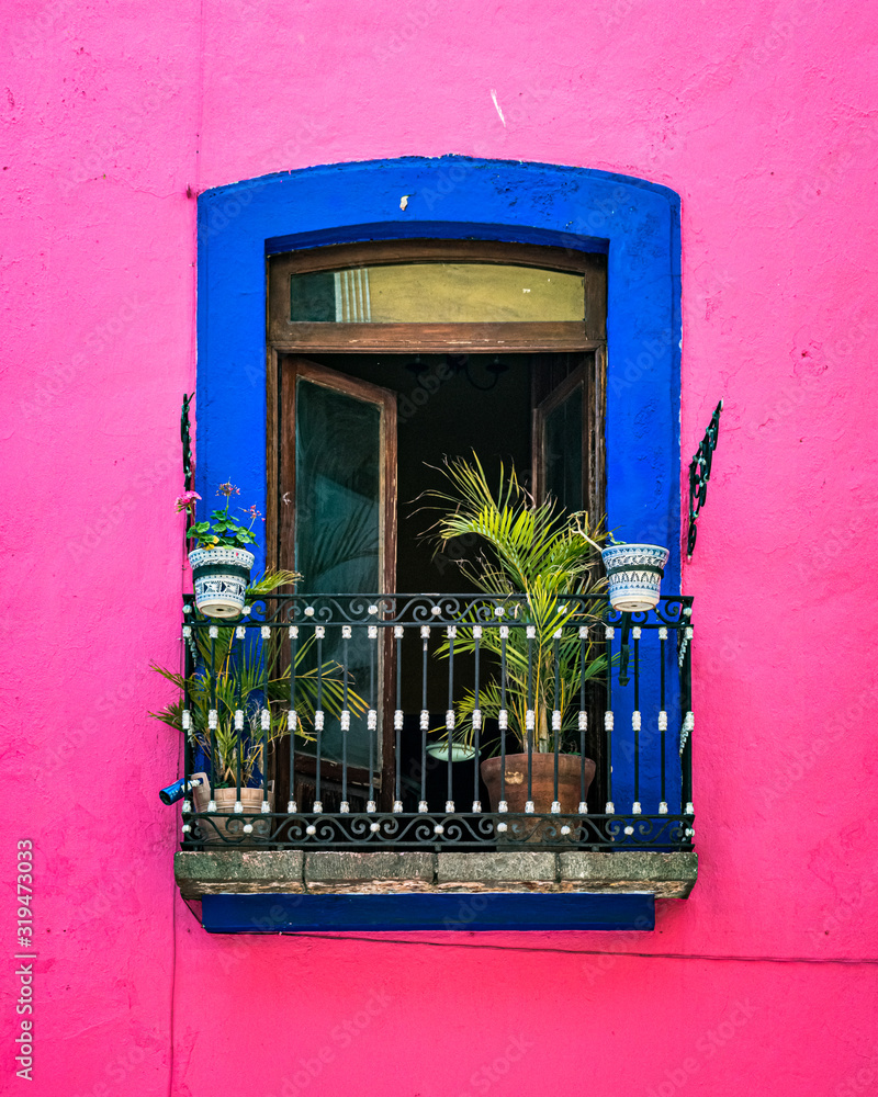 Brightly painted in pink and indigo blue window of a colonial building ...