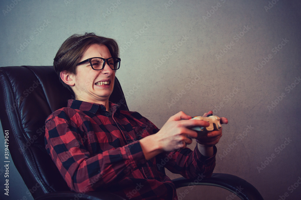Focused teen boy playing video games late night seated in his chair ...