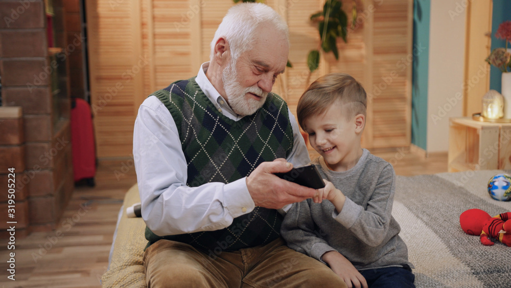 Grandfather and grandson use smart phone at home smiling happy kid ...