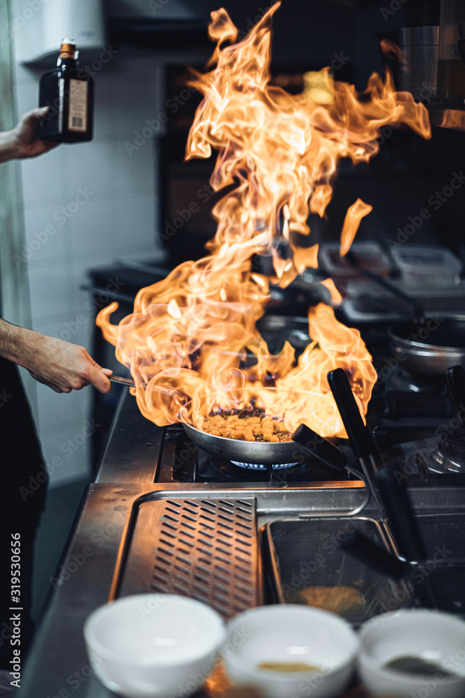 Chef doing flambe while cooking food in restaurant kitchen Stock Photo ...