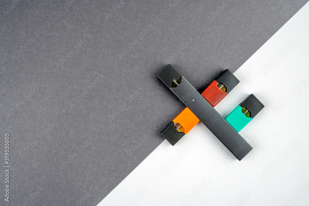 Vaping device and colored vaping pods on grey and white diagonal ...