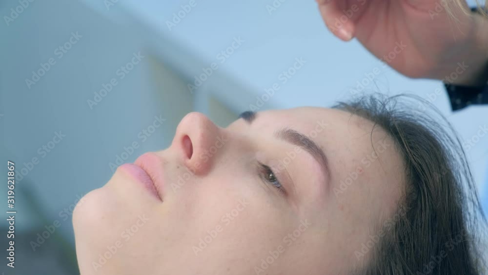 Professional Beautician Plucking Eyebrows With Tweezers To Woman In
