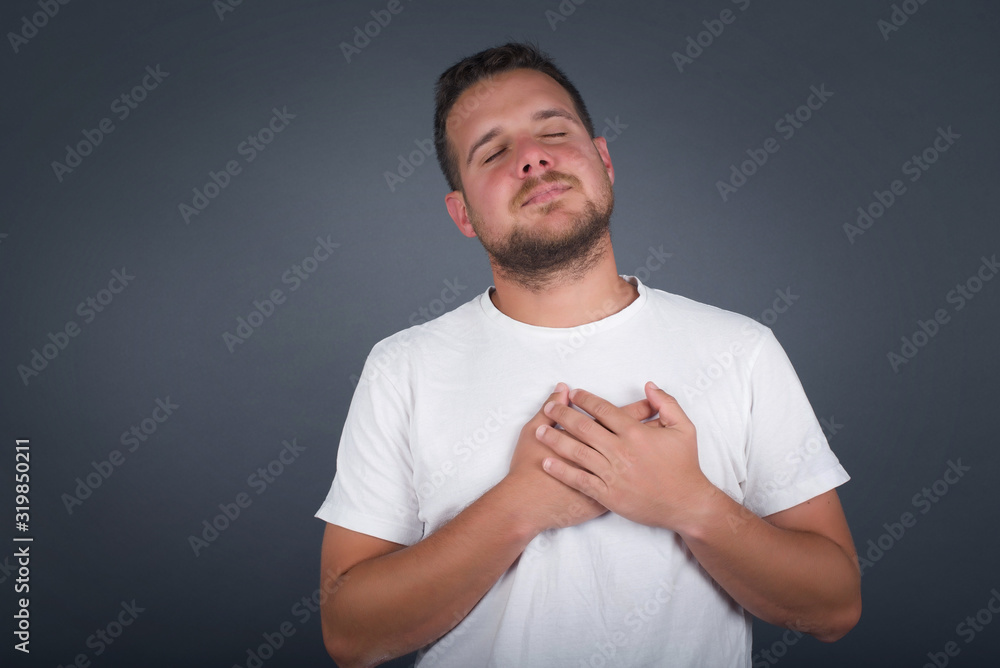 Faithful man closes eyes and keeps hands on chest near heart, shows his ...
