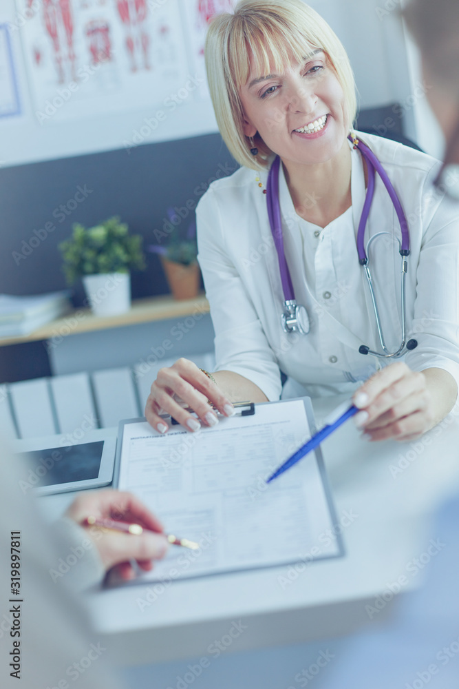 Doctor and patient examining a file with medical records, she is ...