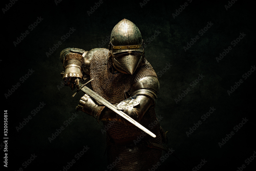 Portrait of a knight in armor, his sword in his hands, performing an ...