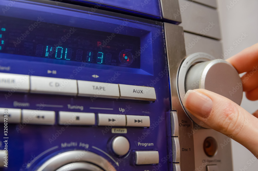 Manual volume control in the music center. A woman's hand adjusts the ...