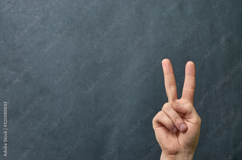 Two fingers up on the hand, peace symbol on a dark background with a ...