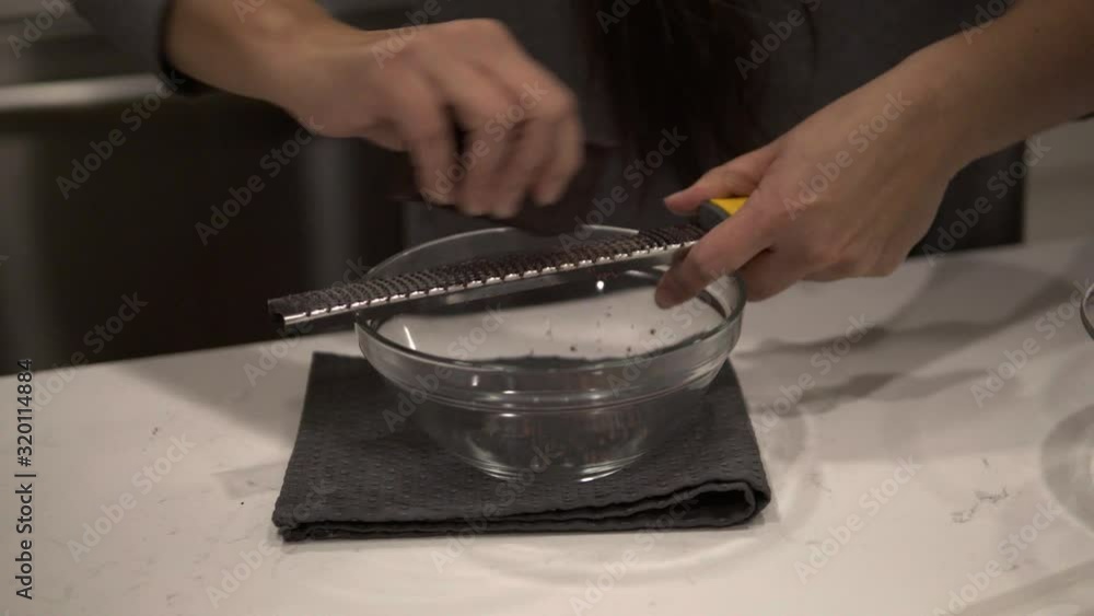 Vidéo Stock A young girl grates chocolate into a bowl for melting while ...