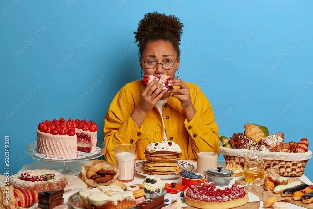 Gluttony and overeating concept. Upset crying ethnic woman eats piece ...
