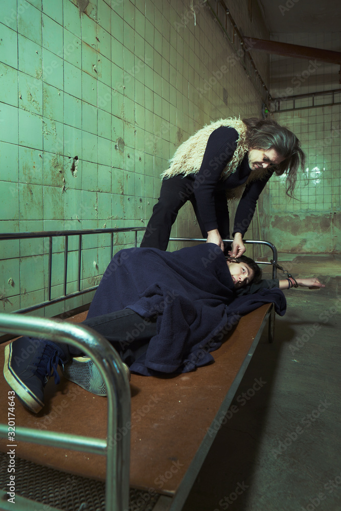 Evil kidnapper holding and controlling young man in horror place Stock ...