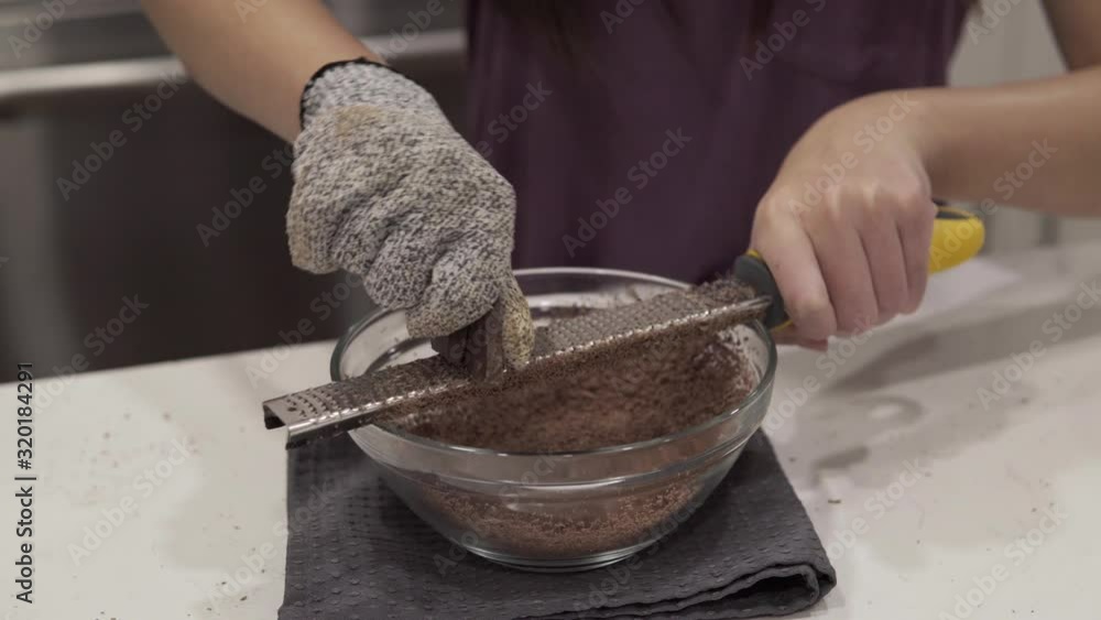 A young girl grates chocolate into a bowl for melting while making ...